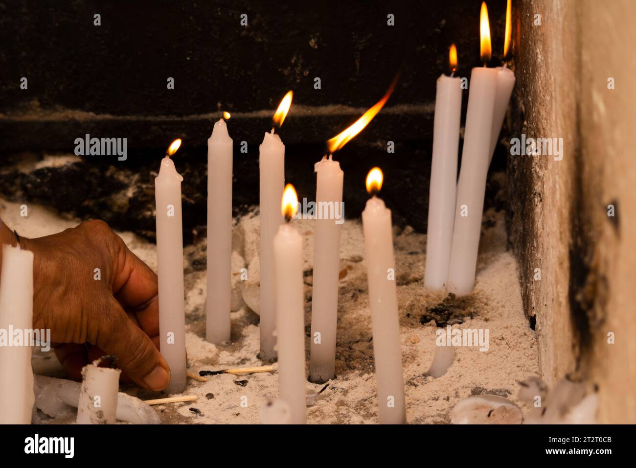 Candles being lit by a human hand. Religious request concept. yellow ...