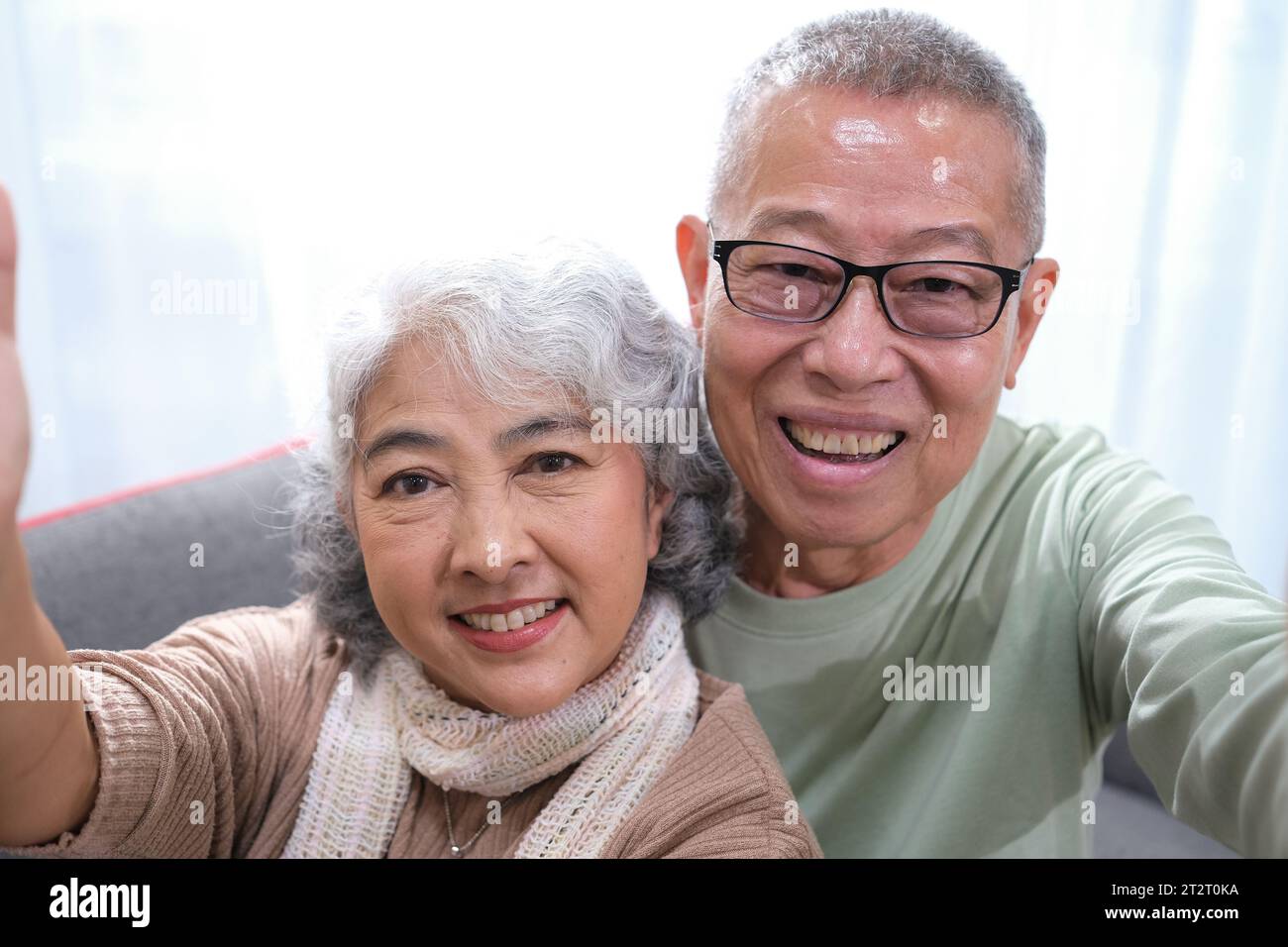 Affectionate senior Asian couple sharing warm embrace on the sofa ...