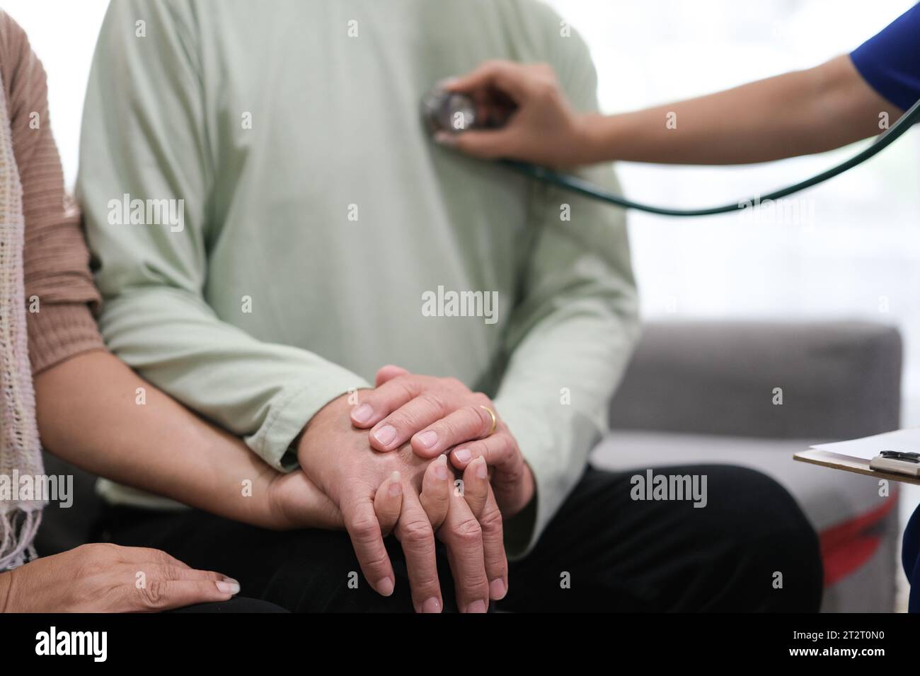 Caring young female doctor examining her contented senior patient with ...