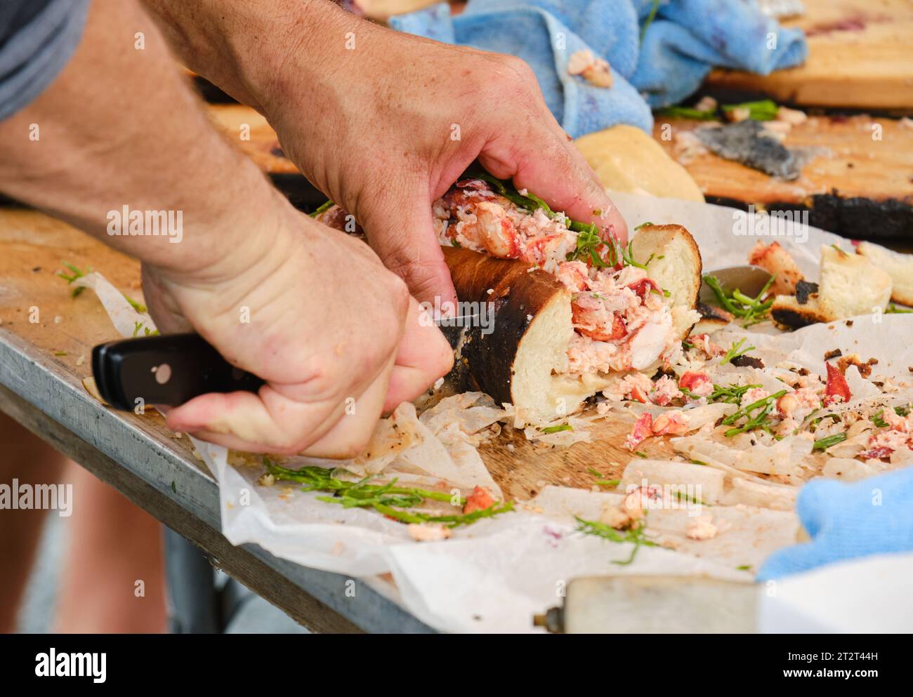 hand slicing an Atlantic Lobster Roll served in bannock, in an ...