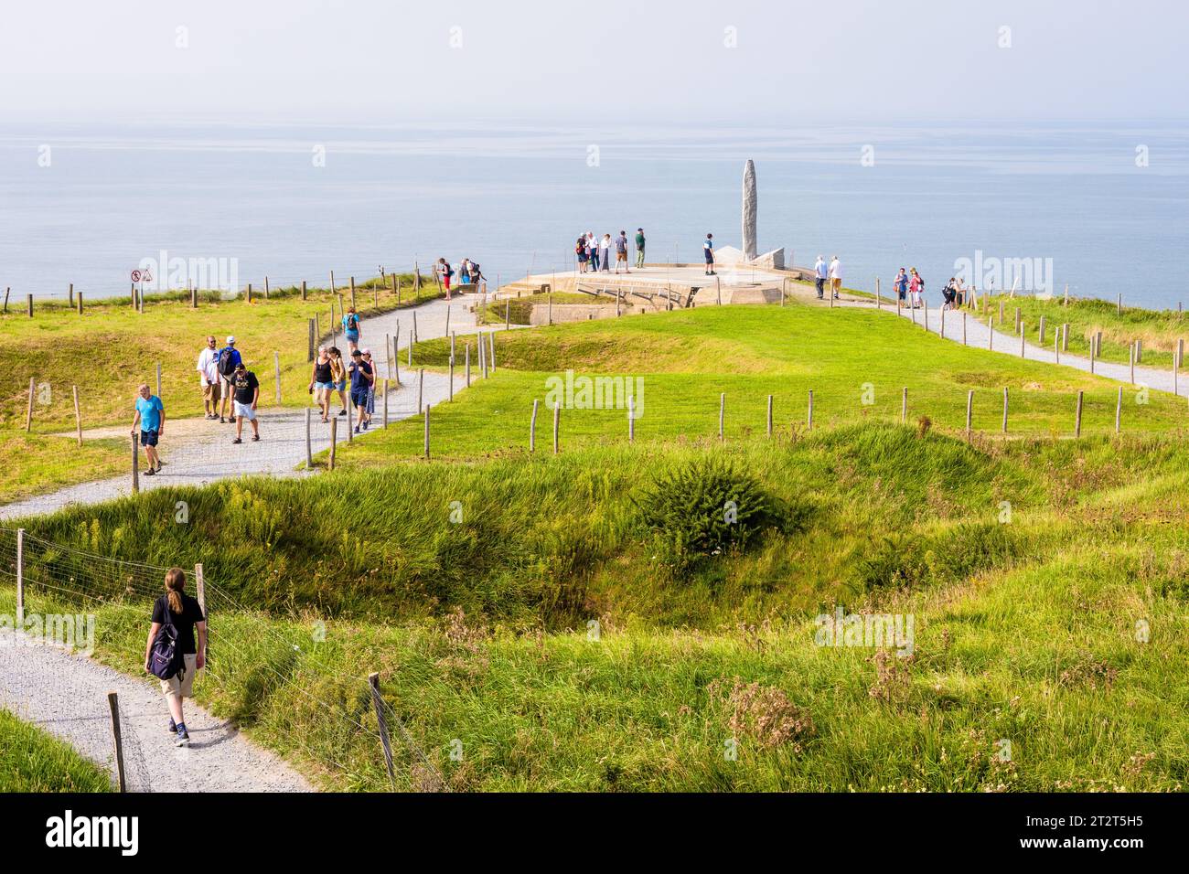 Tourists wander on the Pointe du Hoc path between bomb craters to the ...