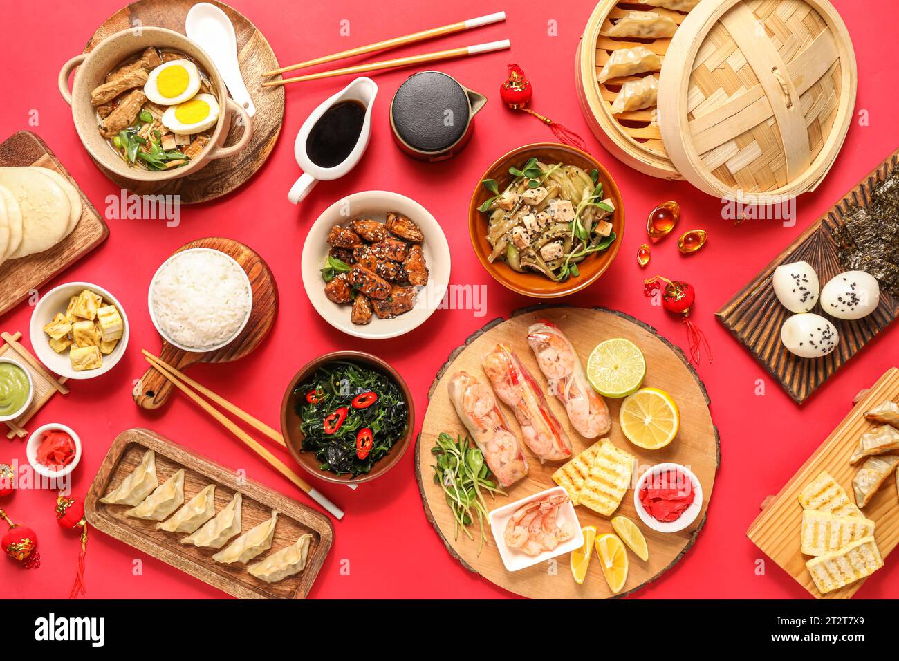 Composition with delicious Chinese dishes and decor on red background ...