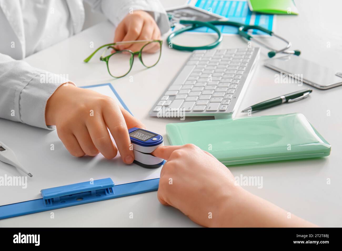 Female doctor taking pulse from patient at white medical desk, closeup ...