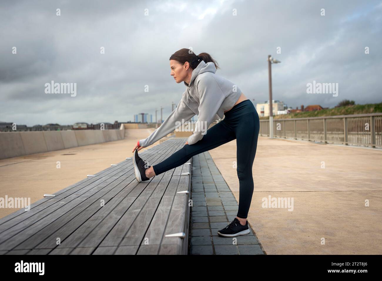 Sporty woman doing leg stretching exercises, outside. Outdoor workout ...