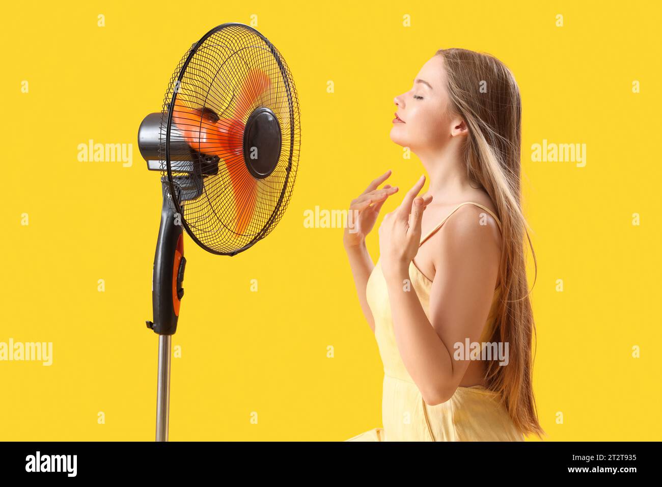 Young woman with electric fan on yellow background Stock Photo - Alamy