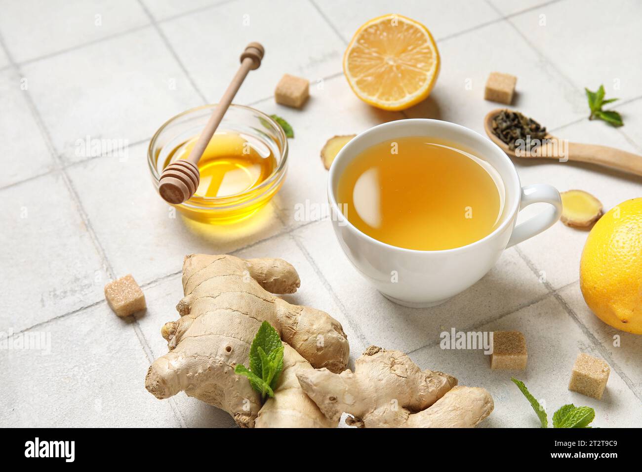 Cup of ginger tea and bowl with honey on white tile background Stock ...