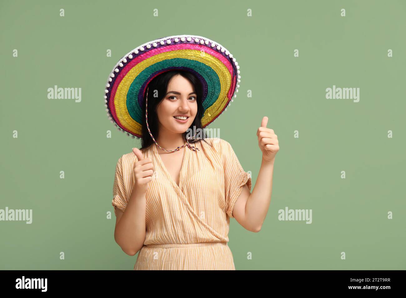 Beautiful Mexican woman in sombrero showing thumb-up on green ...