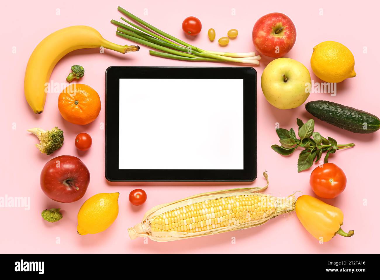 Tablet computer with fruits and vegetables on pink background Stock ...