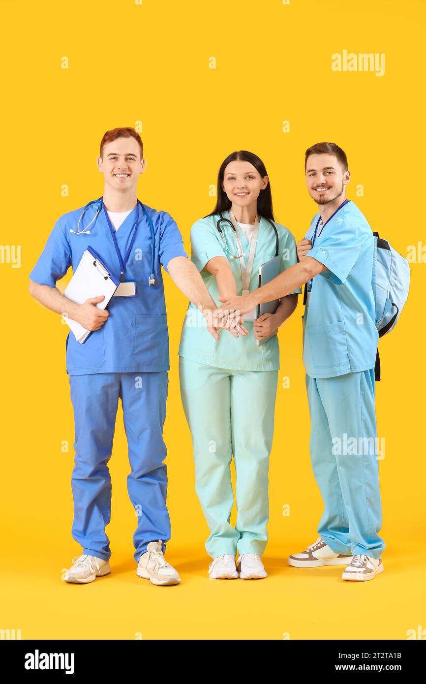 Medical students putting hands together on yellow background Stock ...