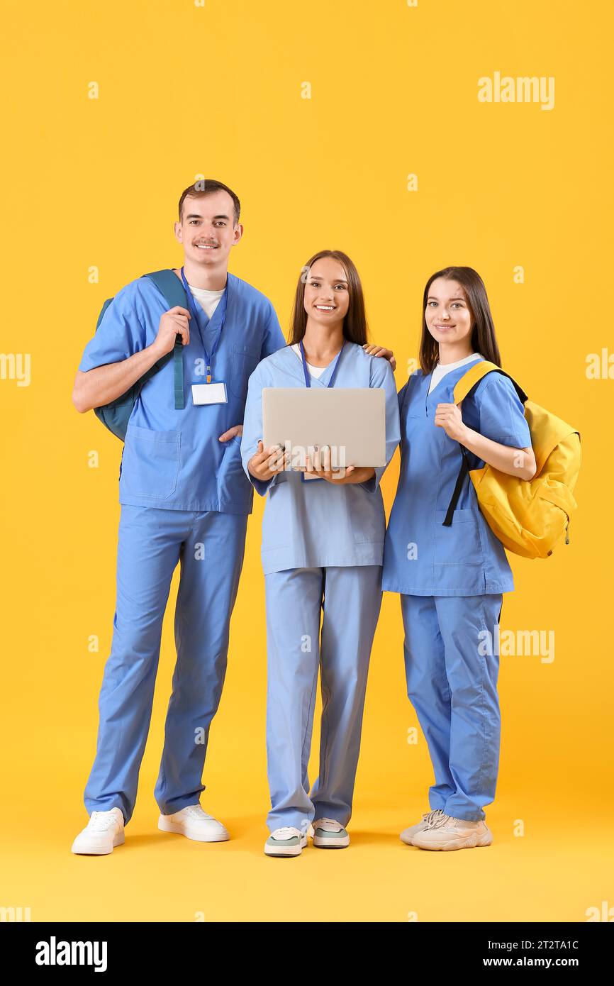 Group of medical students with laptop on yellow background Stock Photo ...