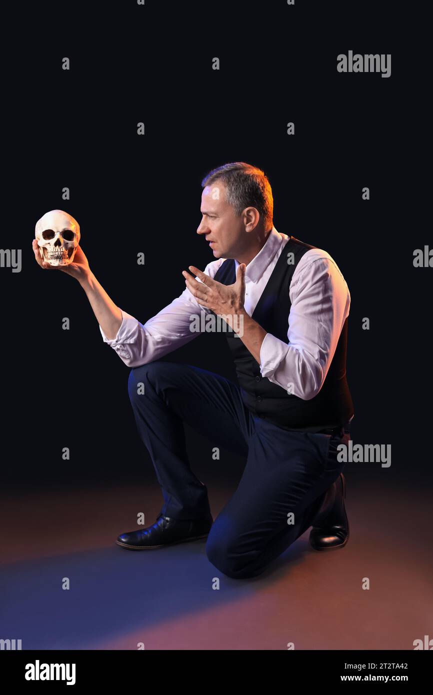 Mature actor with skull on dark background Stock Photo - Alamy