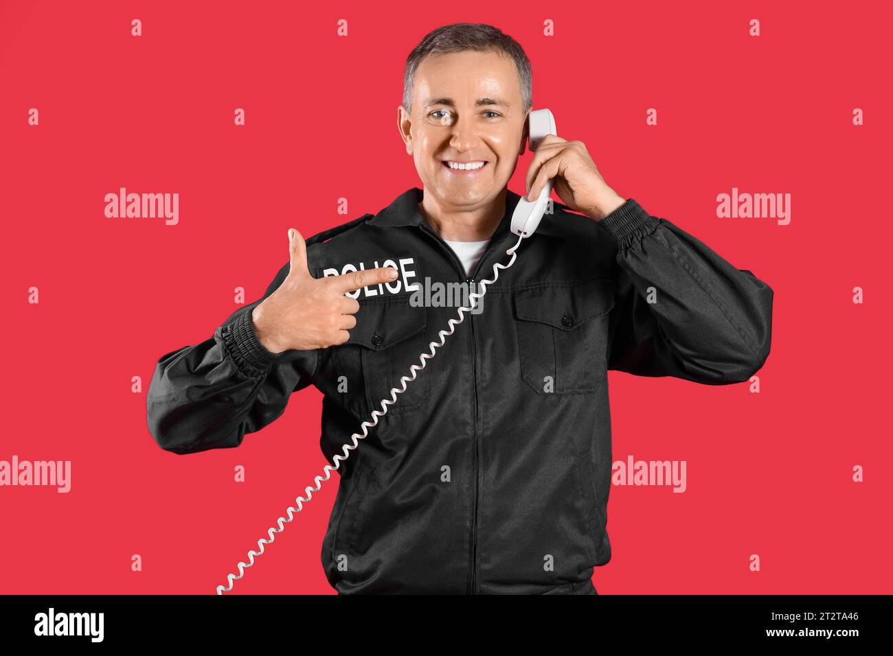 Mature police officer pointing at phone receiver on red background ...