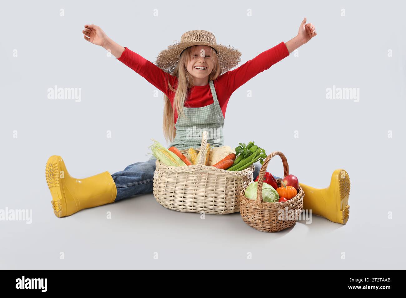 Little farmer with fresh food sitting on light background Stock Photo ...
