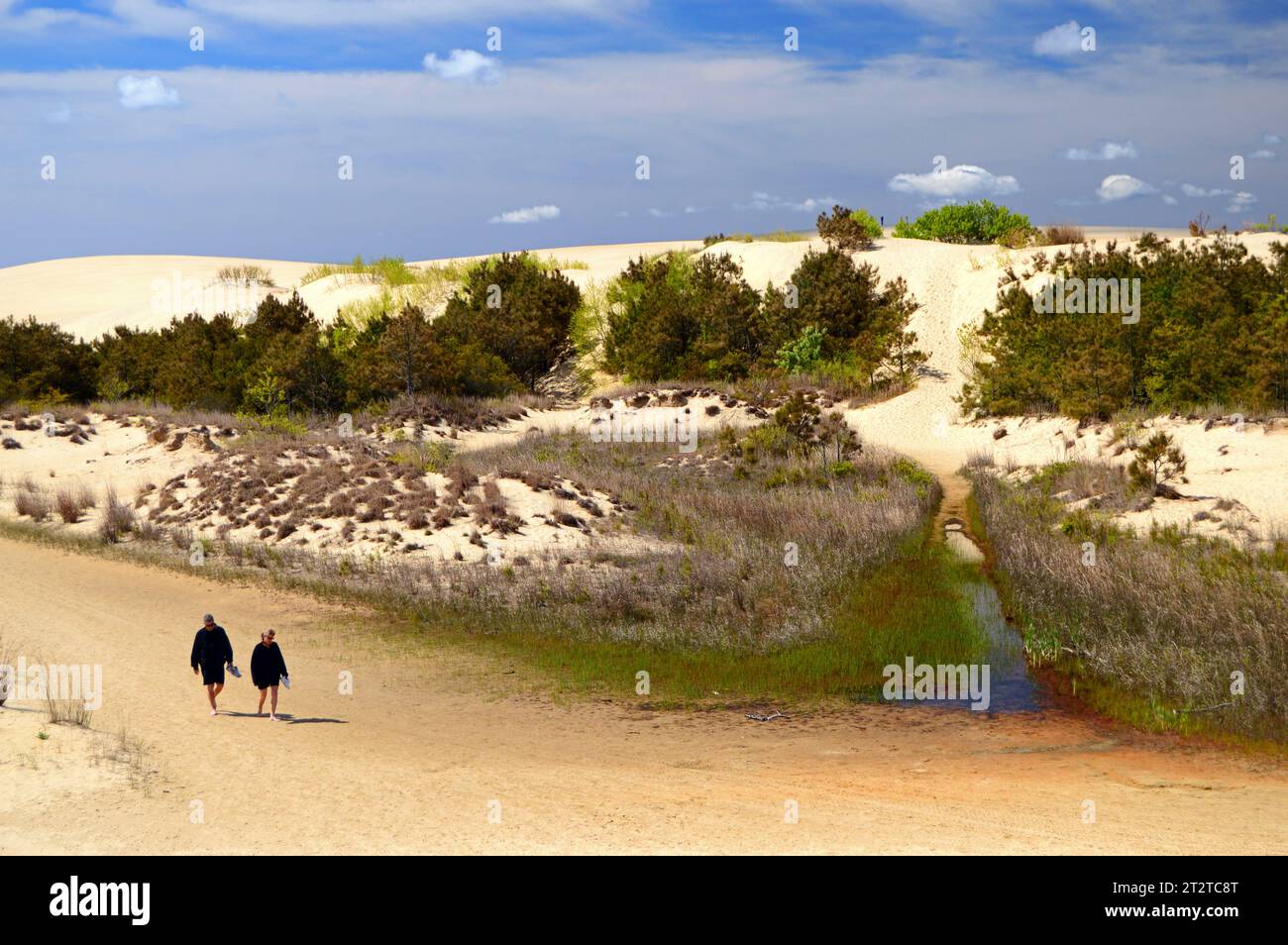A couple walks through a valley in the dune system in Jockey Ridge ...