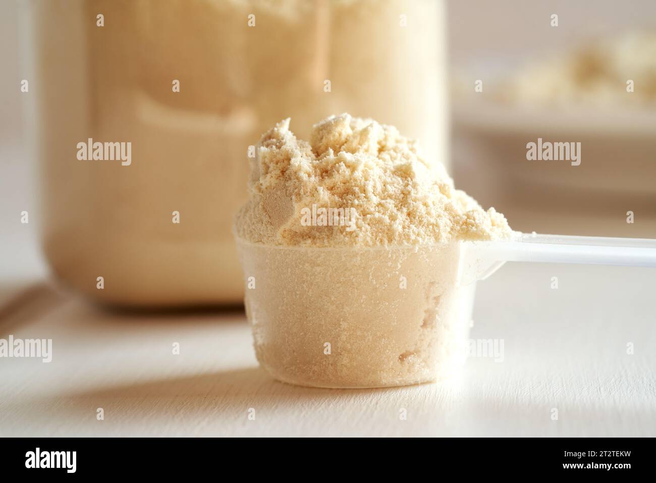 Whey protein powder in a measuring spoon and in a jar on a table Stock ...
