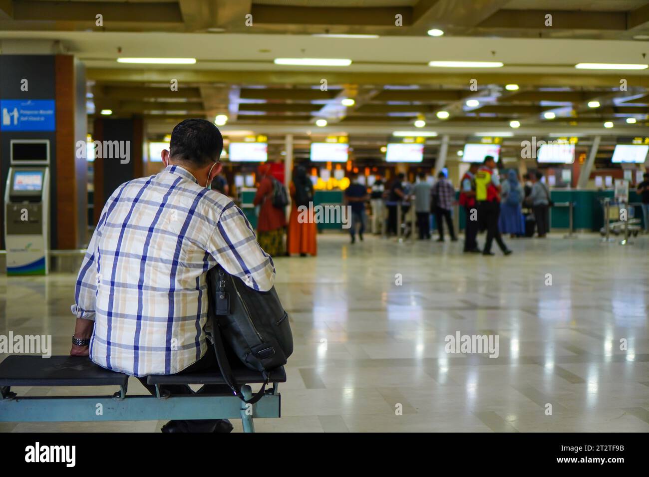 Airport traveler waiting for his turn at the check-in counter. Lonely ...