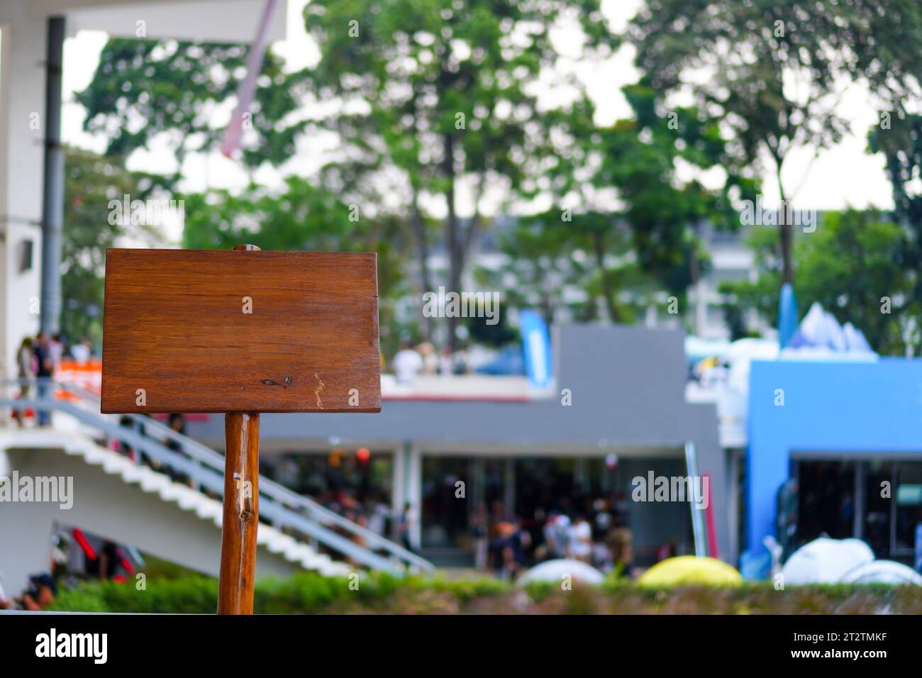 An empty wooden sign for text is shown outside, and a busy crowd can be ...