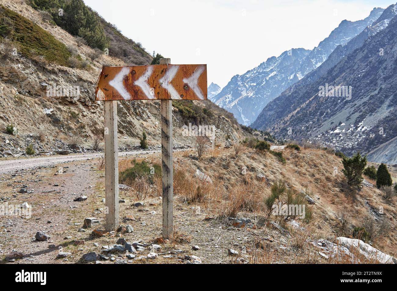 Old road sign indicating a dangerous road turning left in the mountains ...
