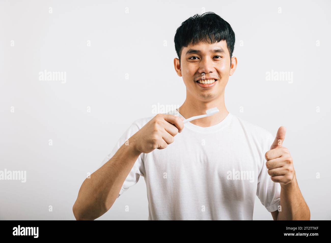 Smiling Asian young man demonstrates proper toothbrushing and approval ...