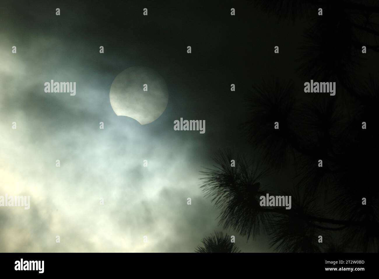 The sun is filtered by clouds in the waning phase of an annular solar ...