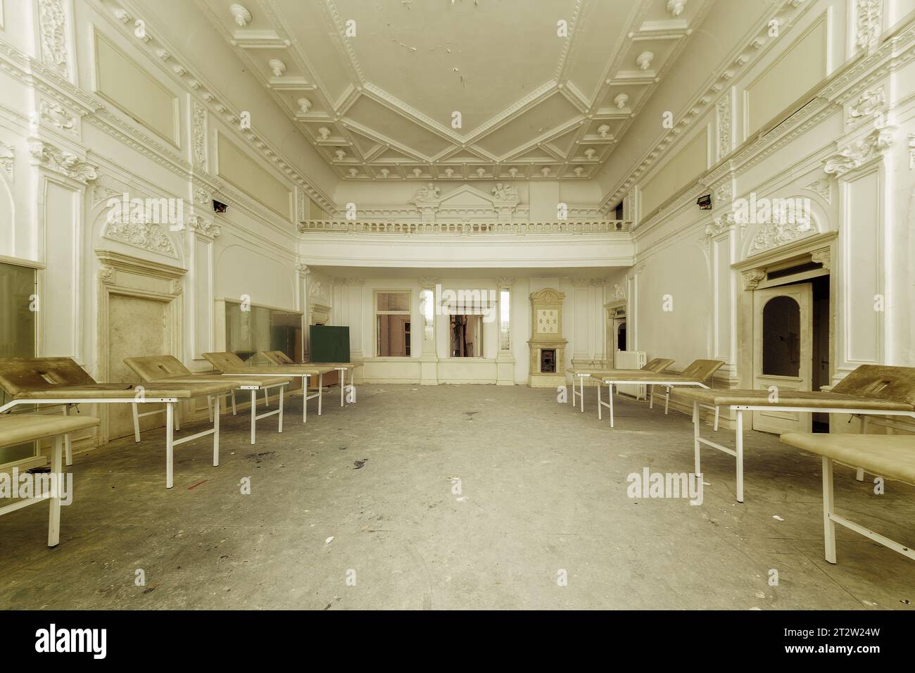An interior of an aged room featuring multiple wooden benches lined up ...