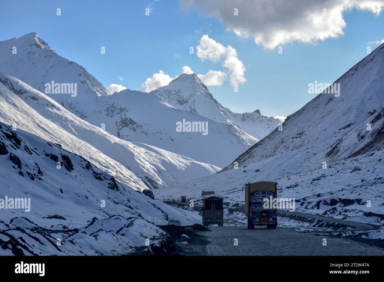 Trucks carrying goods move along the road in Drass, a second coldest ...