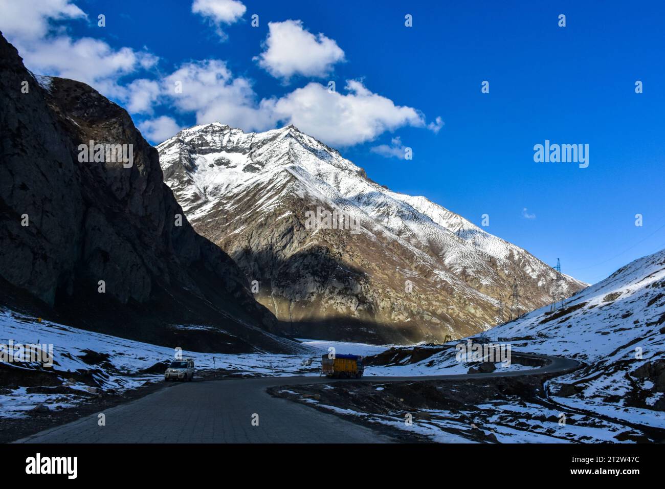 Trucks carrying goods move along the snow covered mountains in Drass, a ...