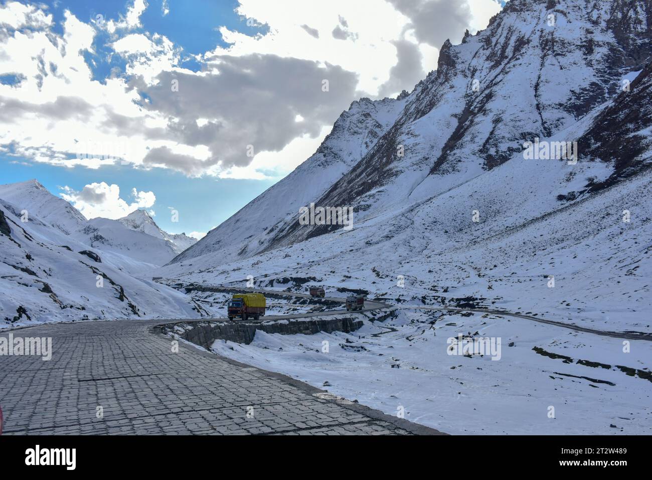 Trucks carrying goods move along the snow covered mountains in Drass, a ...