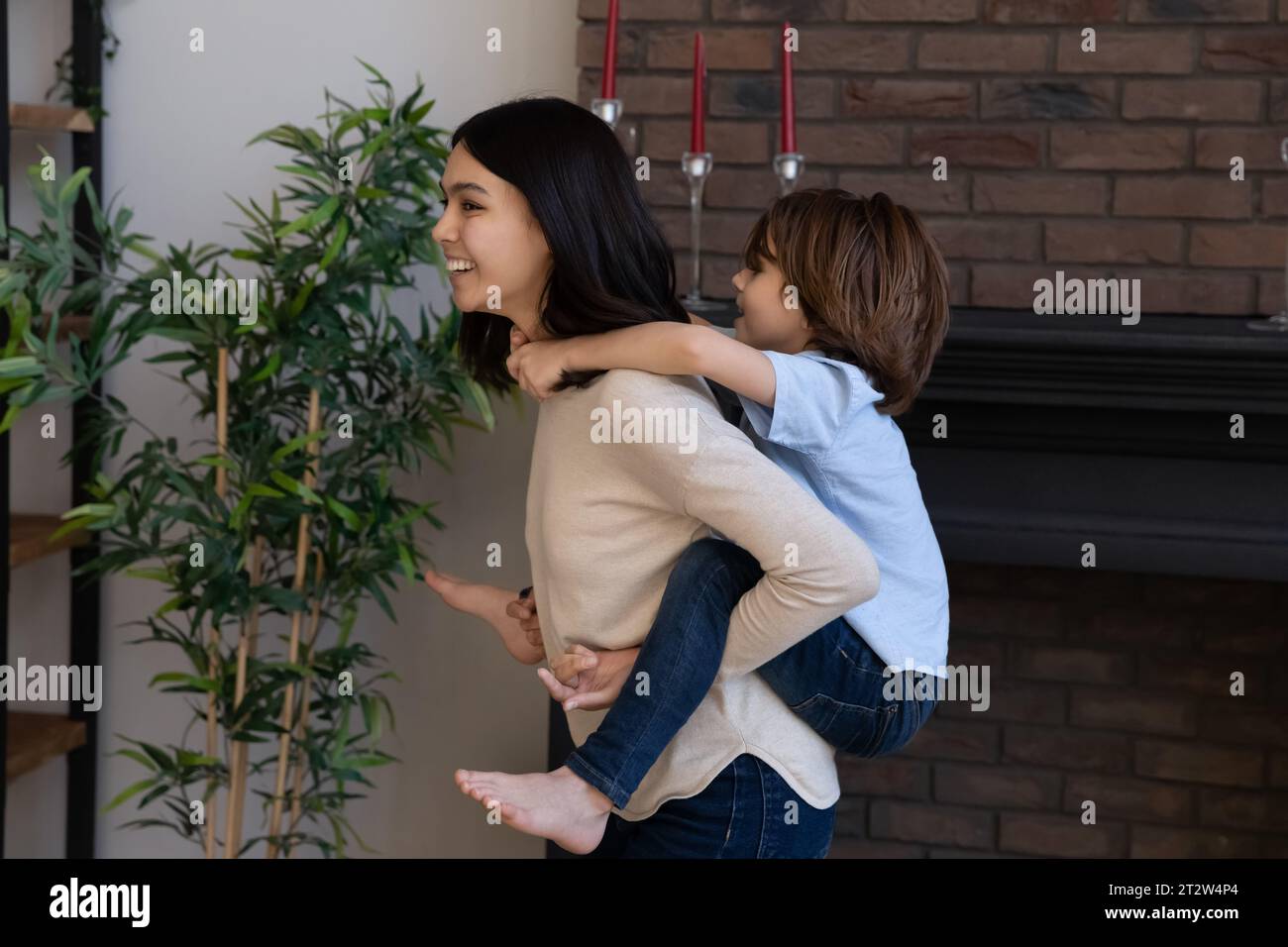 Side view smiling Asian mother piggy backing Caucasian boy Stock Photo ...