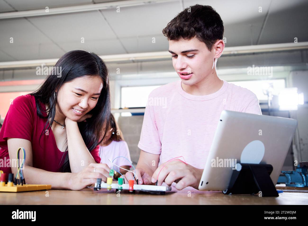 Caucasian boy and Asian girl a technical high school look at a robotic ...