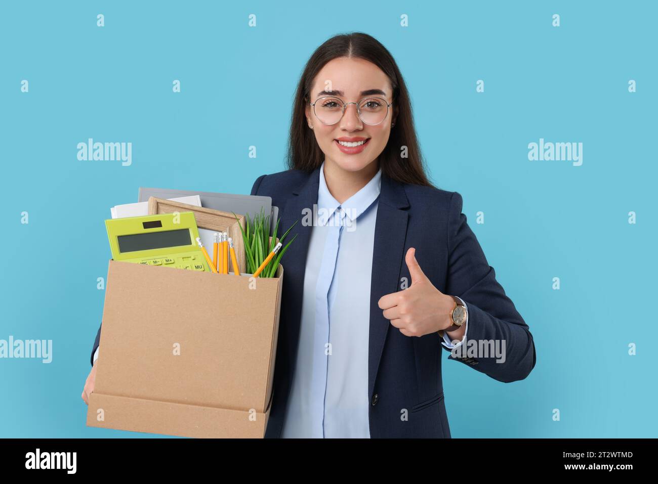 Happy unemployed woman with box of personal office belongings showing ...