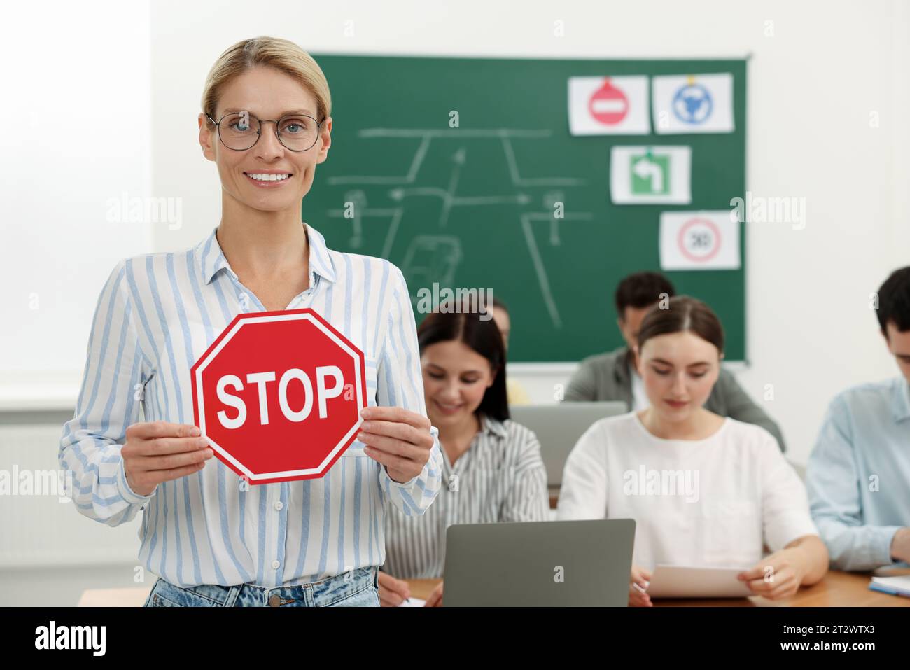 Teacher showing Stop road sign during lesson in driving school Stock ...