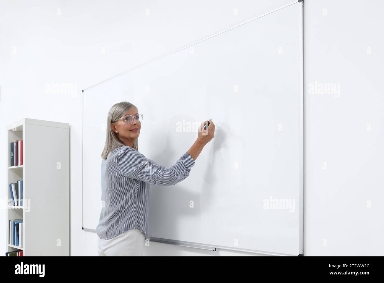 Professor explaining something at whiteboard in classroom, space for ...