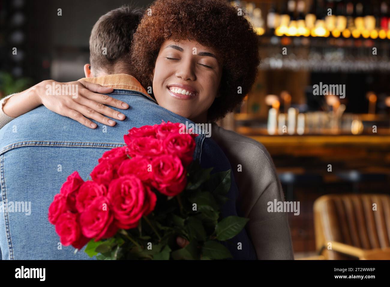 International dating. Beautiful woman with bouquet of roses hugging her ...