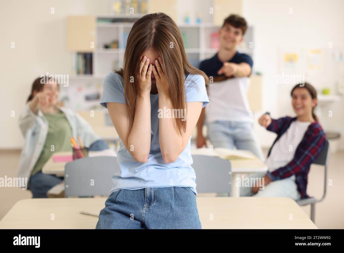 Teen problems. Students pointing at upset girl in classroom, selective focus Stock Photo - Alamy