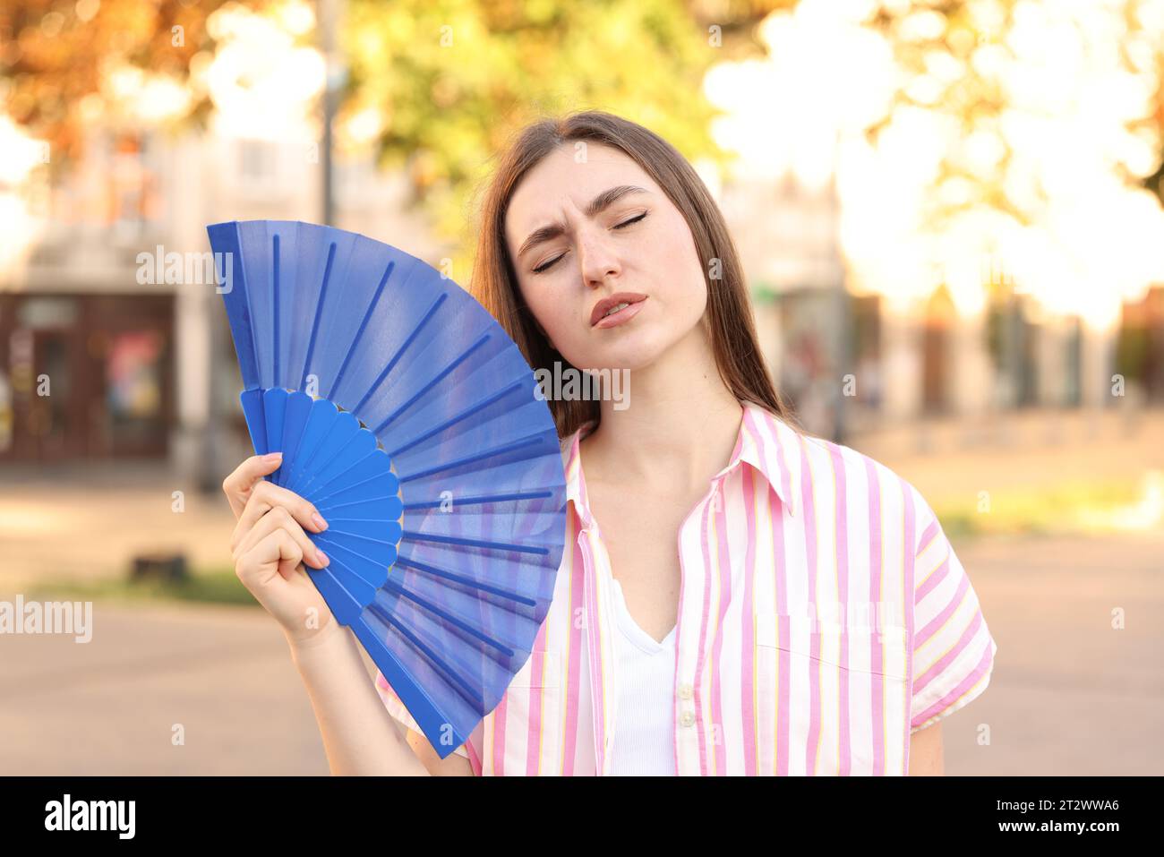 Woman with hand fan suffering from heat outdoors Stock Photo - Alamy