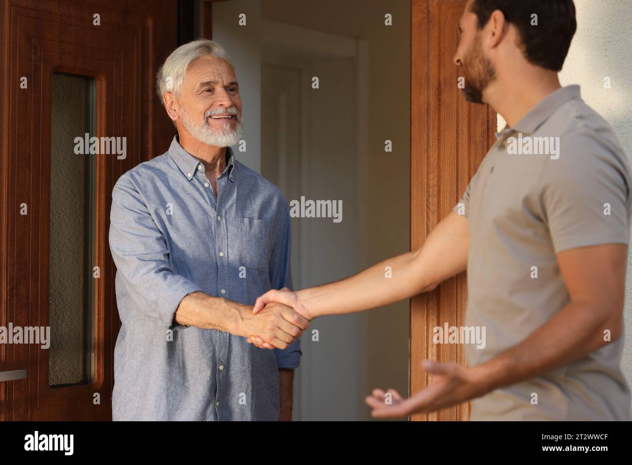 Friendly relationship with neighbours. Happy men shaking hands near ...