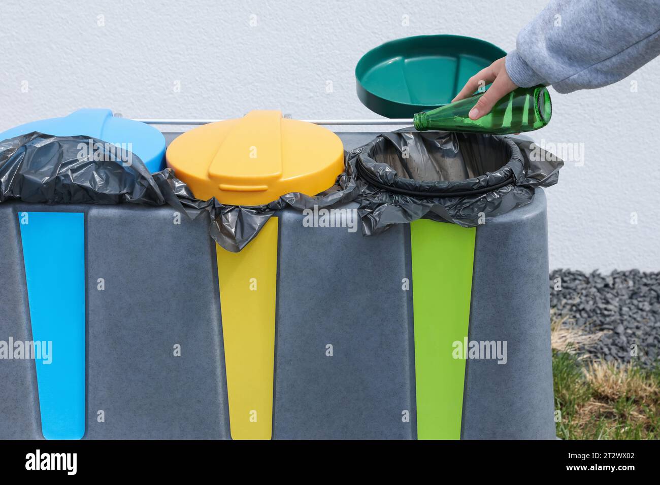 Woman throwing glass bottle in bin outdoors, closeup. Recycling concept ...