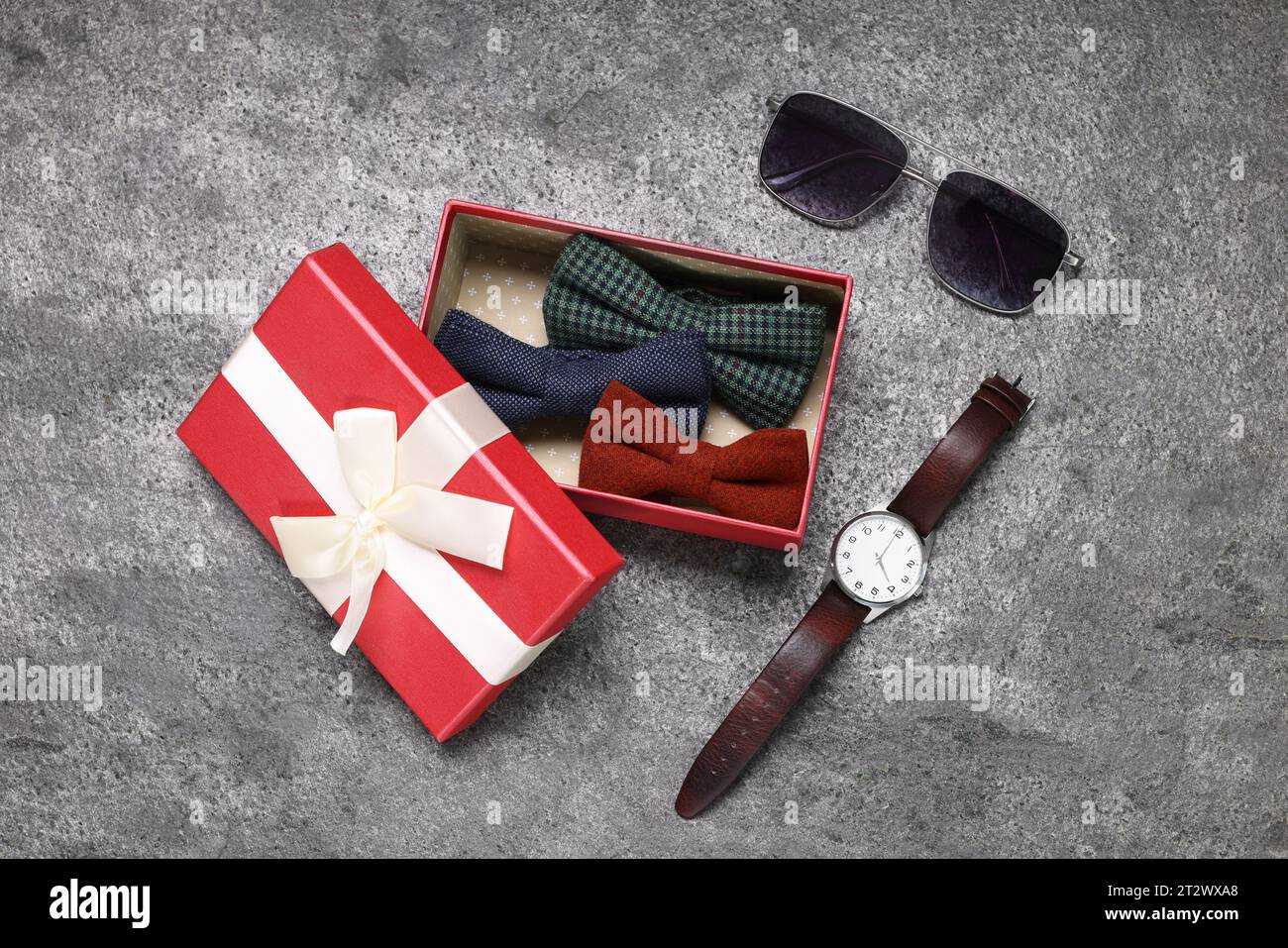 Stylish color bow ties in gift box, wristwatch and sunglasses on grey ...