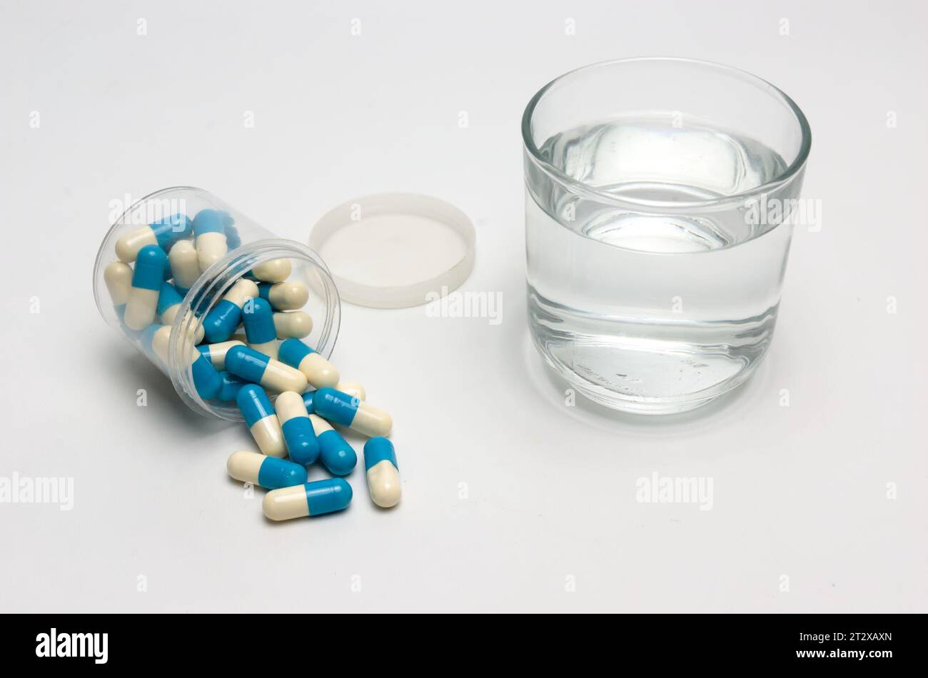 A glass of water and medical capsules on the table ready to be consumed ...