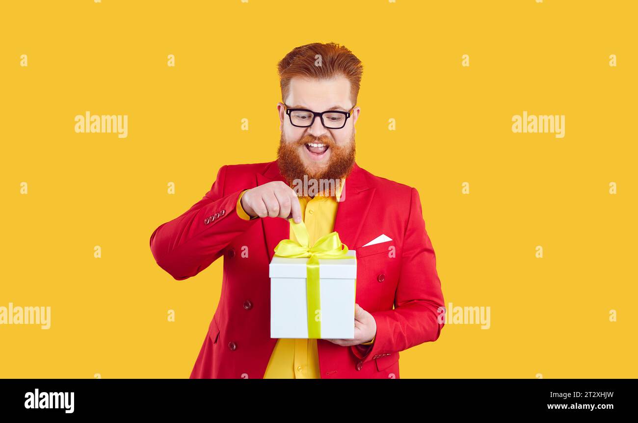 Funny happy excited bearded fat man opens gift box isolated on vivid ...