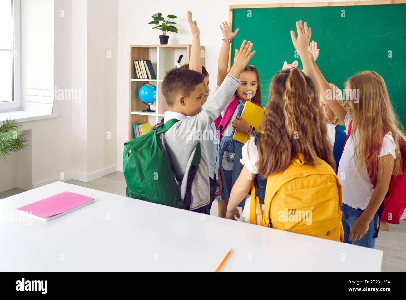 Elementary school students are having fun talking and raising their ...