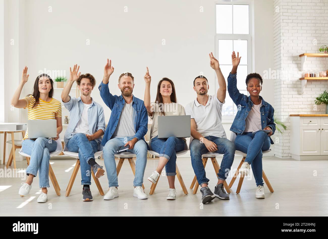 Business people sitting in row on seminar training raising their hands ...