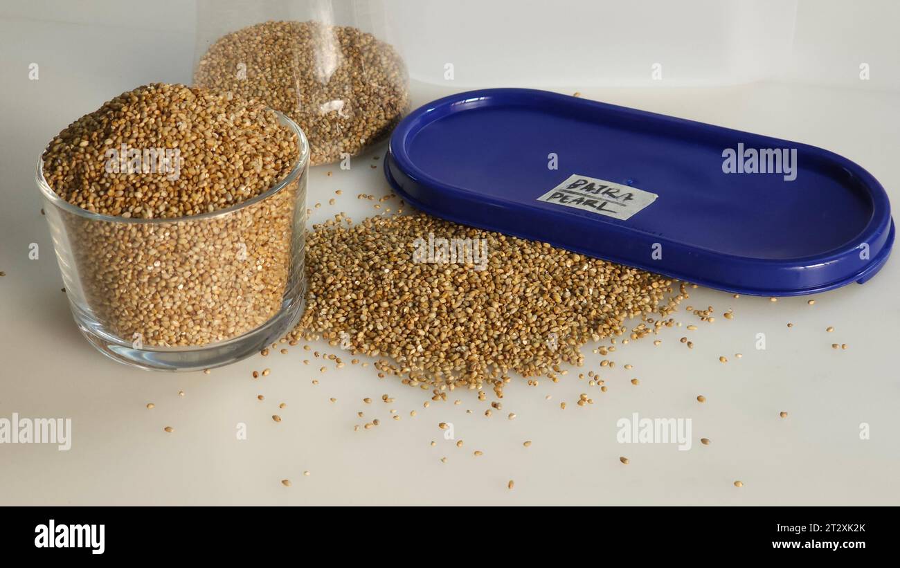 Pearl millet grains in a storage container and glass bowl filled to the ...