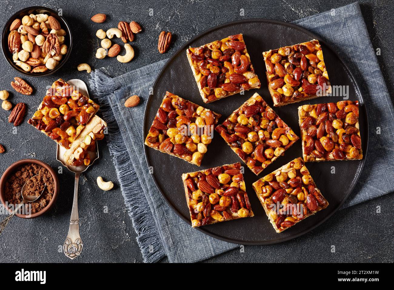 homemade toffee mixed nuts shortbread bars on black plate on grey ...