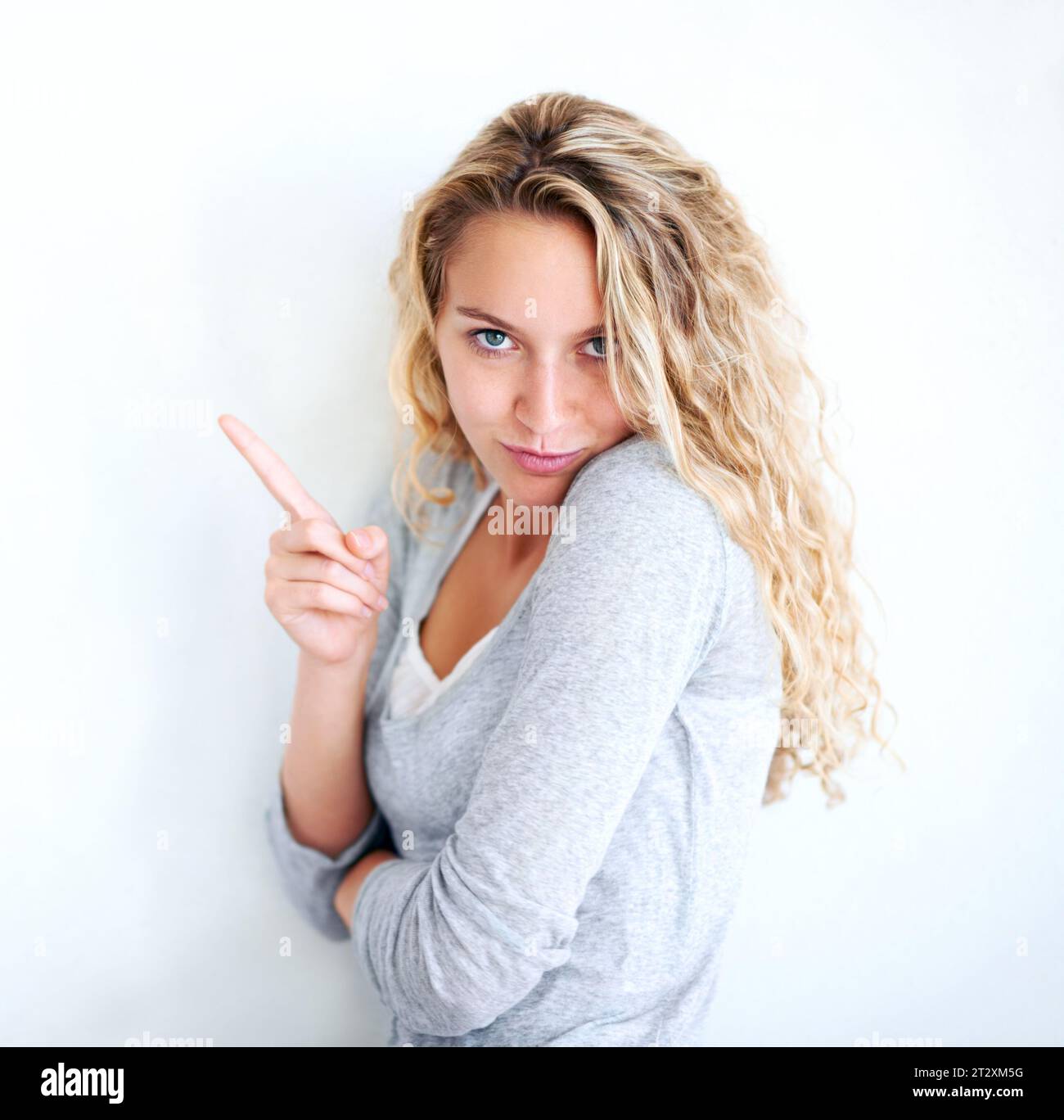 Woman, portrait and pointing finger playful or flirt fun, white wall ...