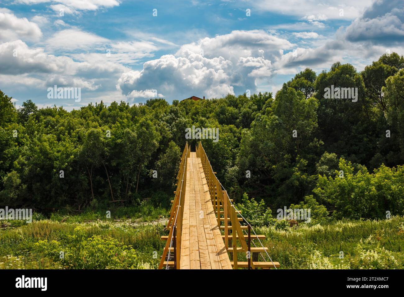 Colorful rural landscape with a view of a wooden footbridge over a ...