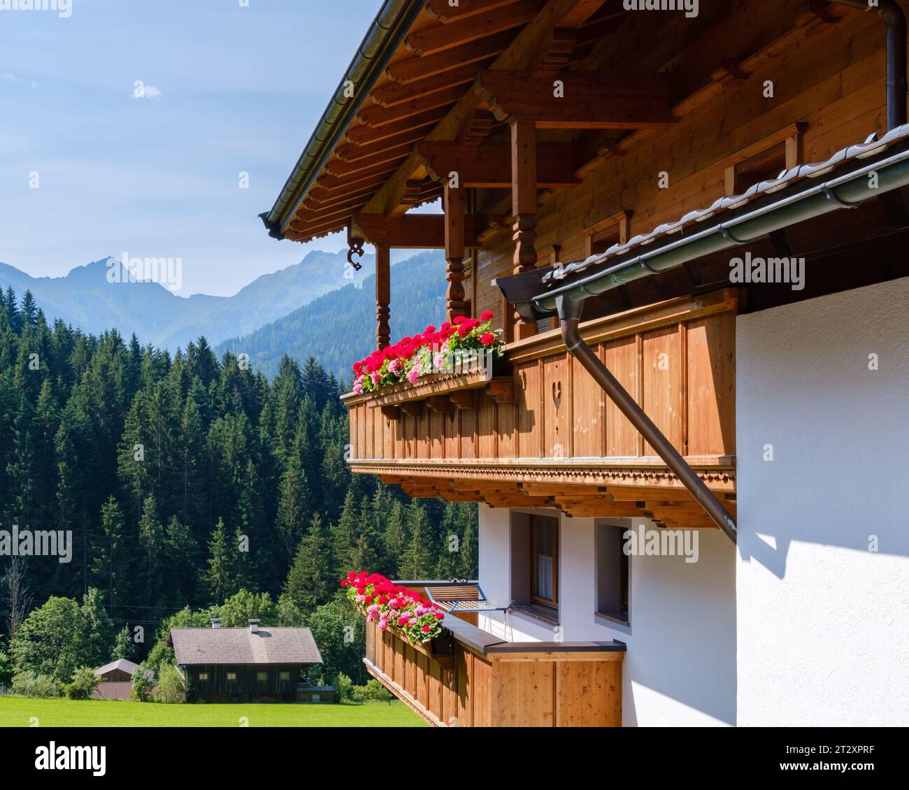 Traditional wooden alpine houses with flowers on balcony, mountain ...