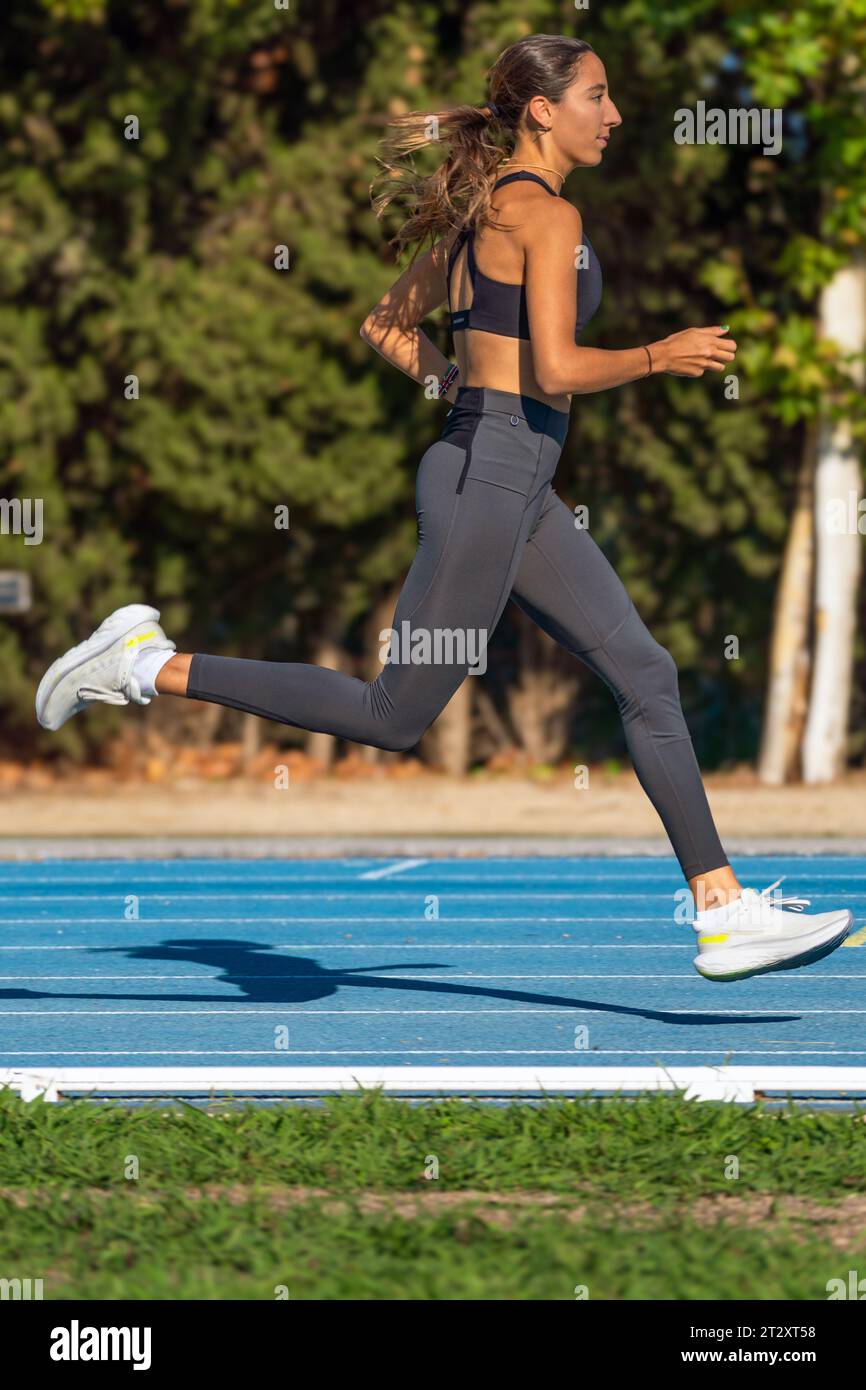 Beautiful young slim tanned runner girl, concentrated, dressed in tight ...