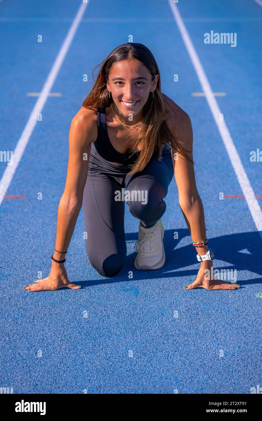 Beautiful young runner, tanned with long dark hair, smiling at the ...